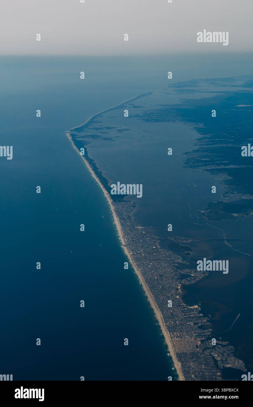 Aerial view shows a long sandy peninsula reaching into calm waters and ...