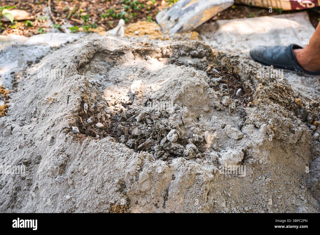Construction worker manually mixes sand, cement, and water on the ...