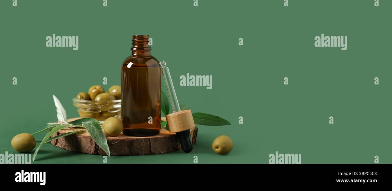 Bottle of olive essential oil on green background with space for text ...