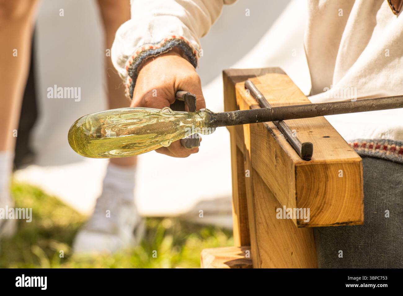 Glassblower or glassworker sculpting a section of the molten glass with ...