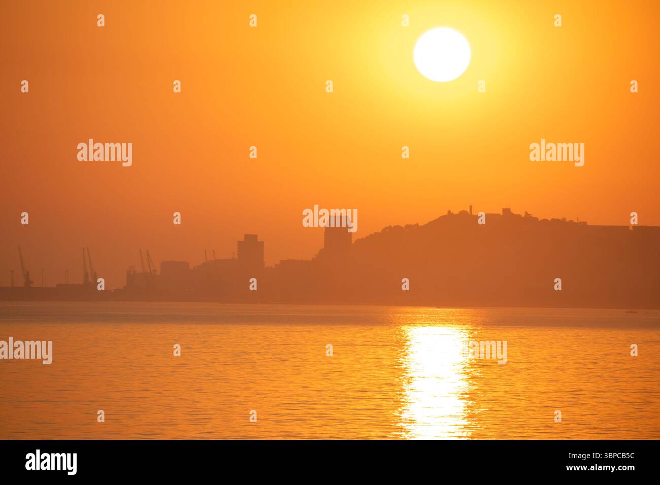 vibrant golden hour sunset casts an orange glow over a city skyline ...
