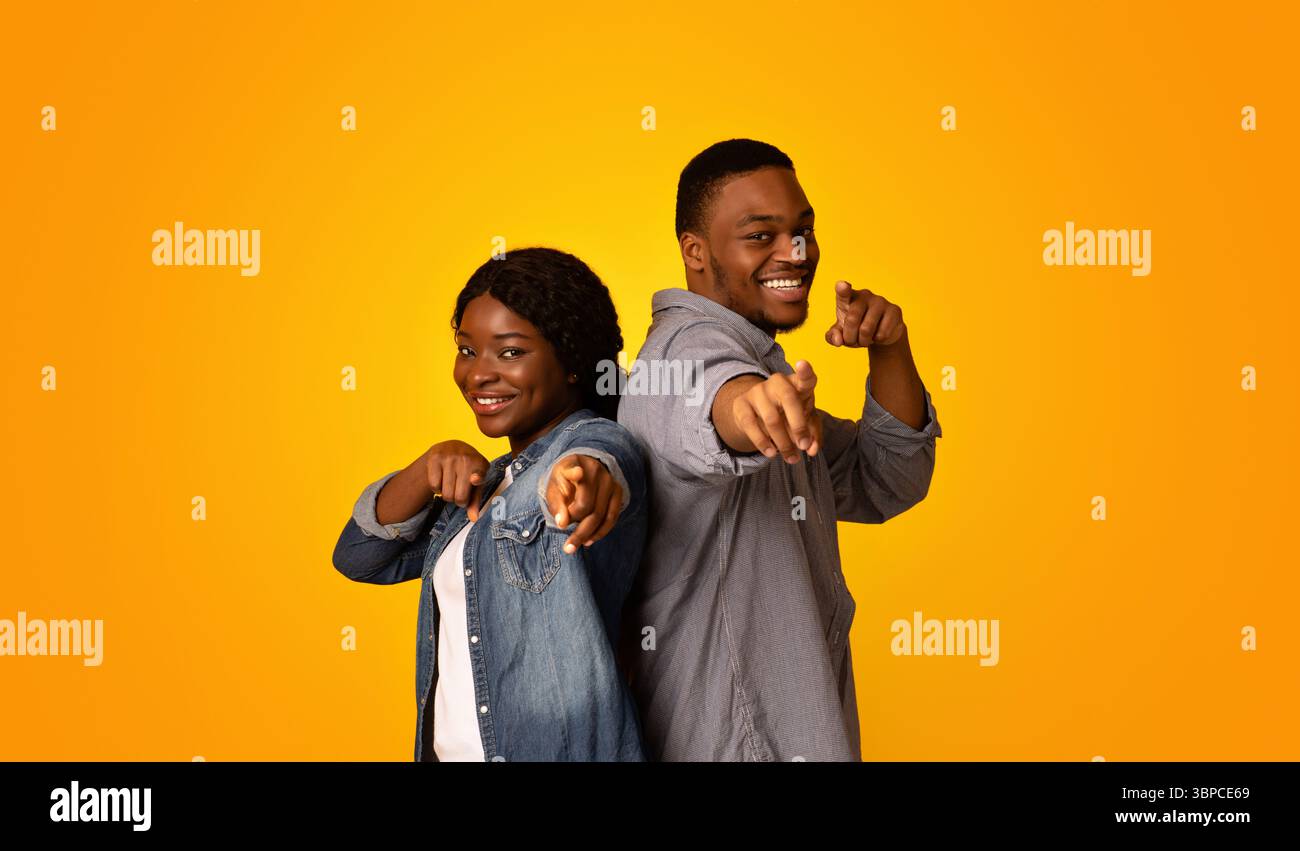 Gotcha. Joyful african man and woman pointing at camera with fingers ...