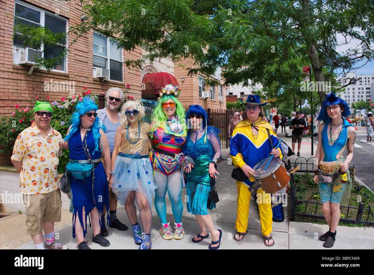 A group of eight adults, dressed in vibrant costumes, pose on a city ...