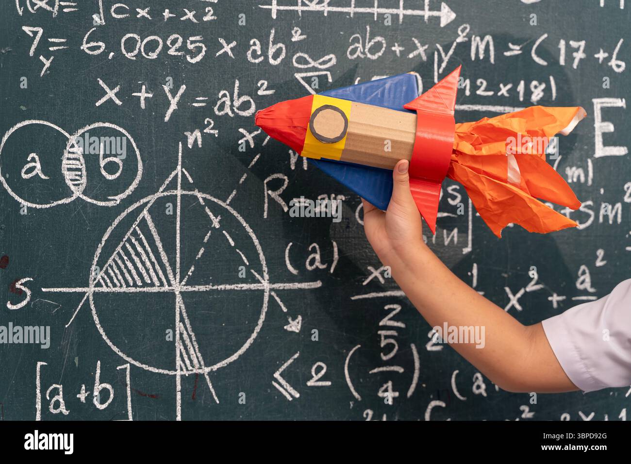 Close-up of student hand holding colorful handmade rocket craft against ...