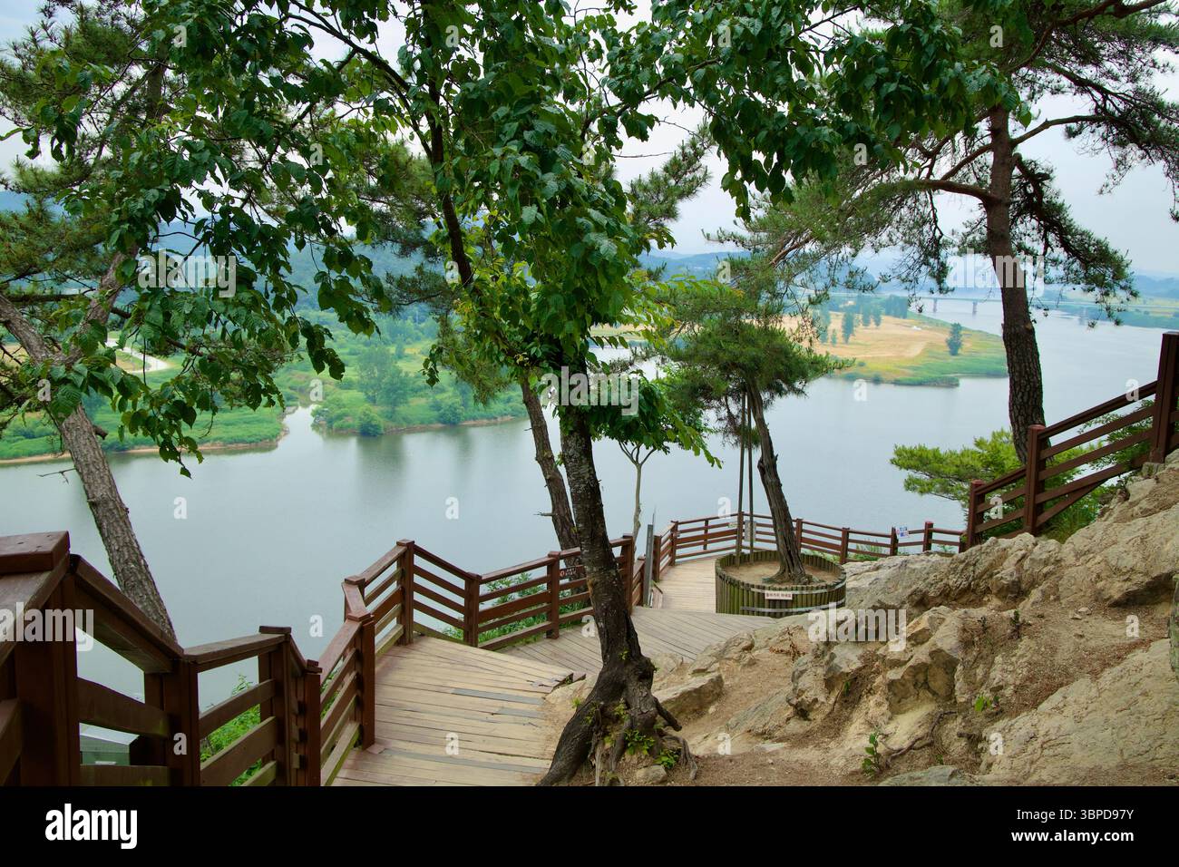 Buyeo County, South Korea - June 13th 2025: A curved wooden viewing deck near Nakwaam Rock wraps ...