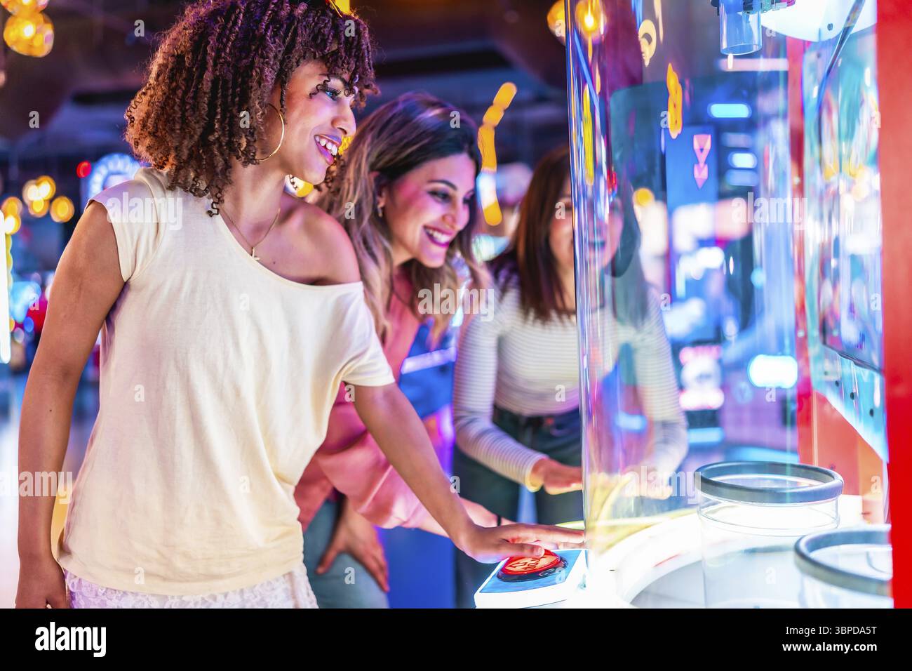 Three friends enjoying their time together playing an arcade game in a ...