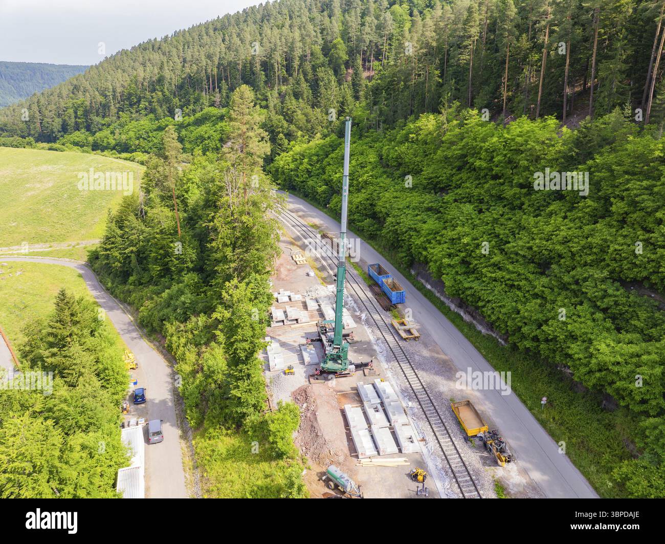 Construction work along a railway line in a green forest area, crane ...