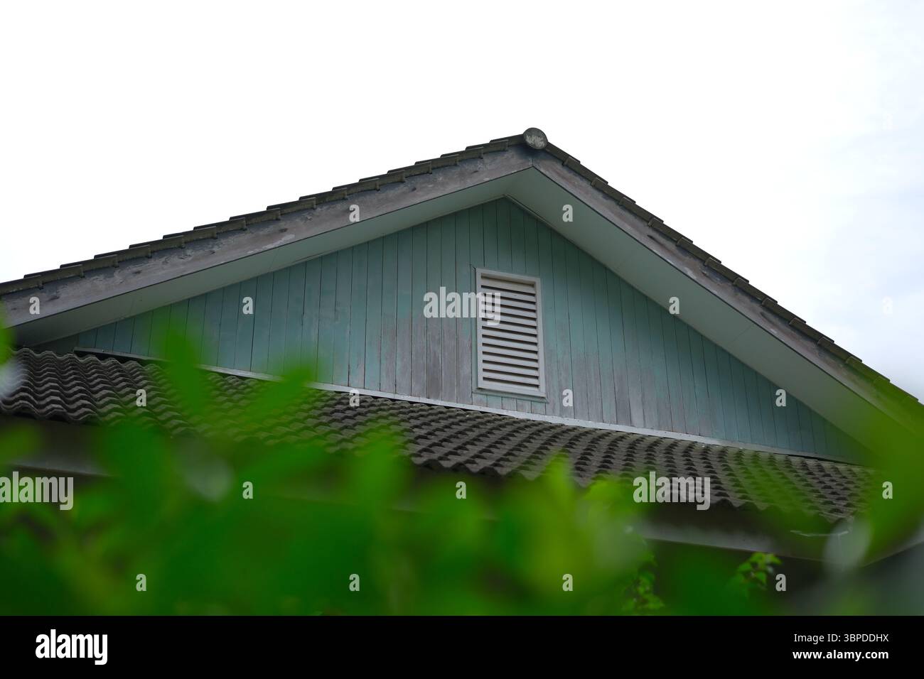 Rustic countryside cottage gable with weathered teal siding, louvered ...