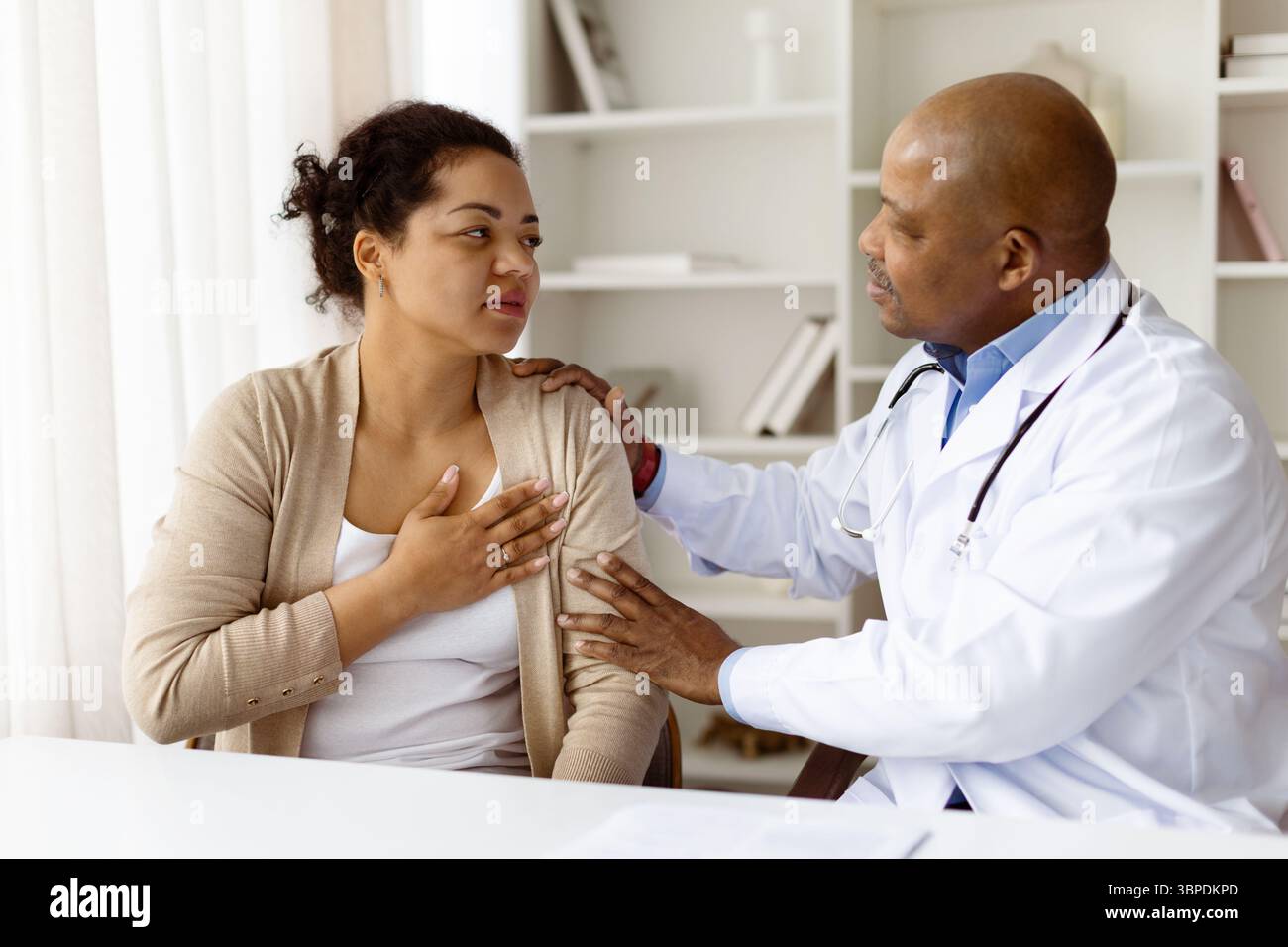 Compassionate doctor placing hand on female patients shoulder during ...