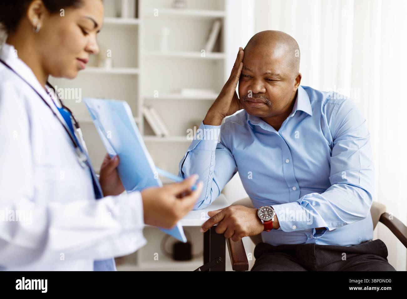 Concerned black male patient touching head while listening results of ...