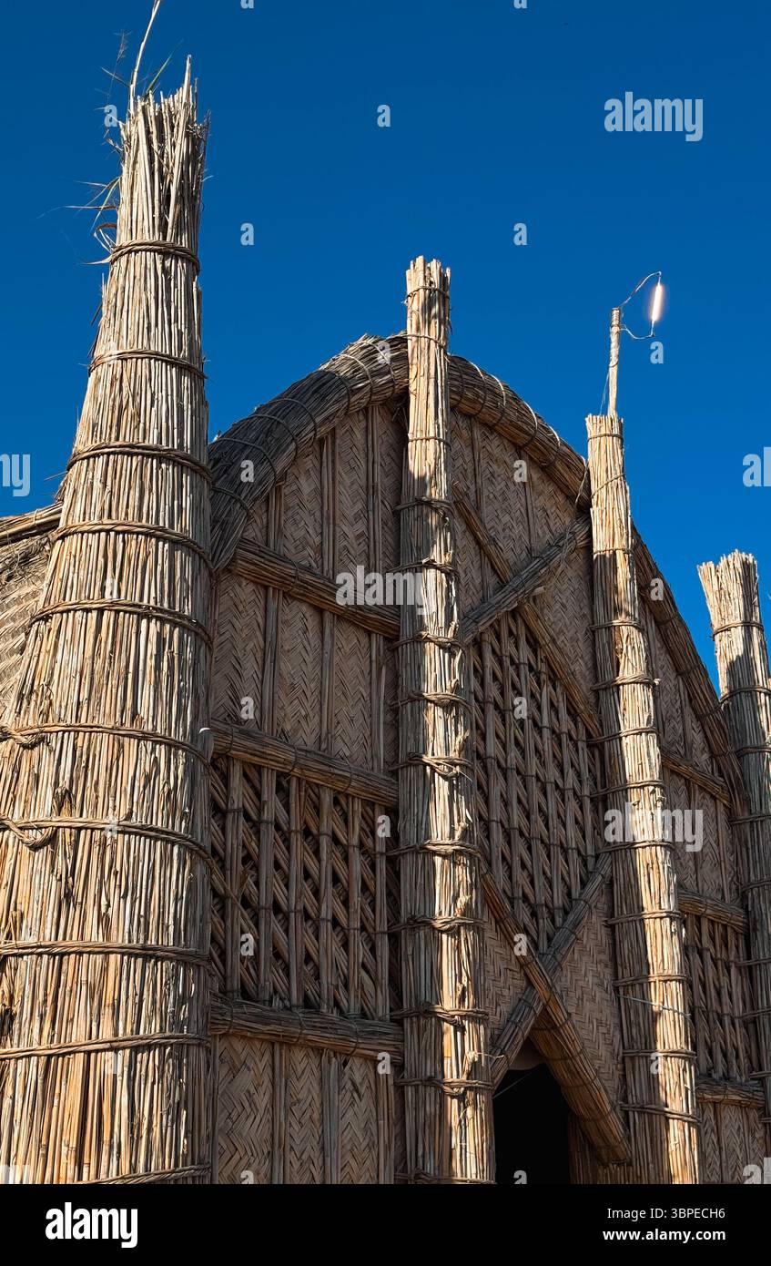 Straw structures reflect Iraqi architecture against a bright blue sky ...