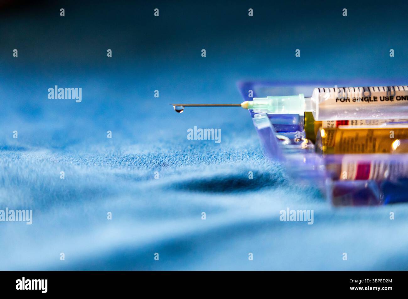 single-use medical syringe with medicine droplets and empty drug bottle ...