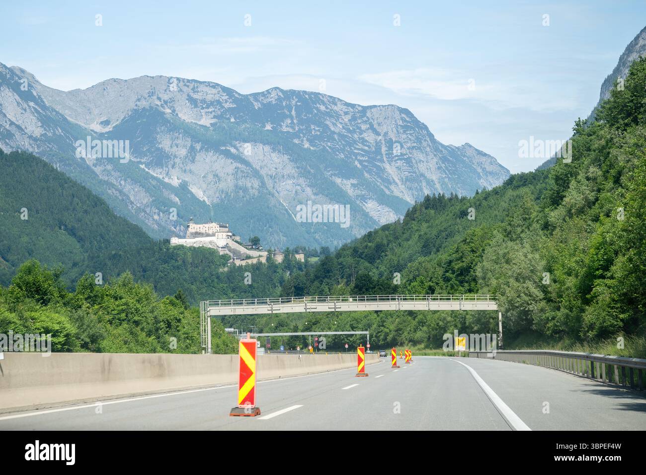 Mountain highway with castle in distance and road construction signs ...