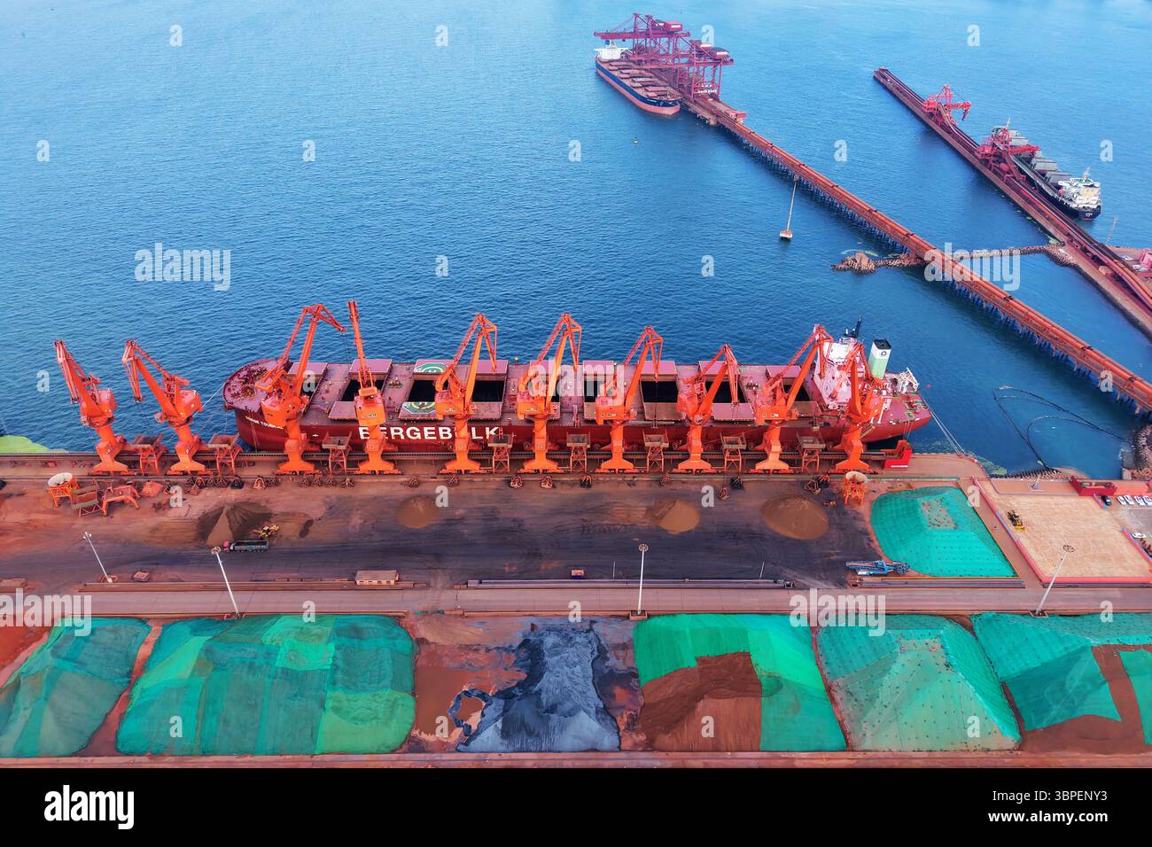 A cargo ship is unloading imported iron ore at the ore terminal of ...