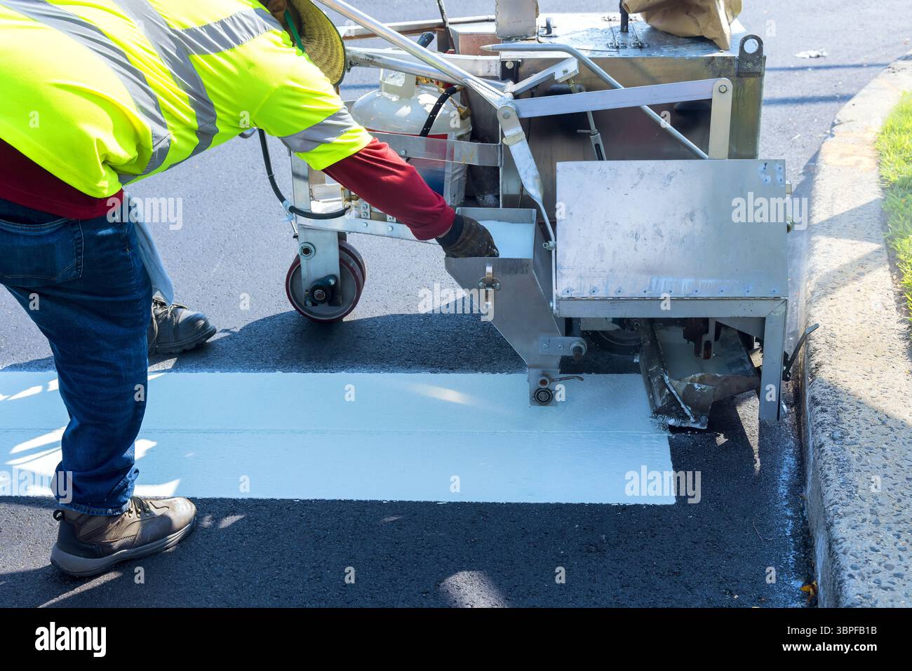 Worker uses specialized machine to paint white line on freshly laid ...