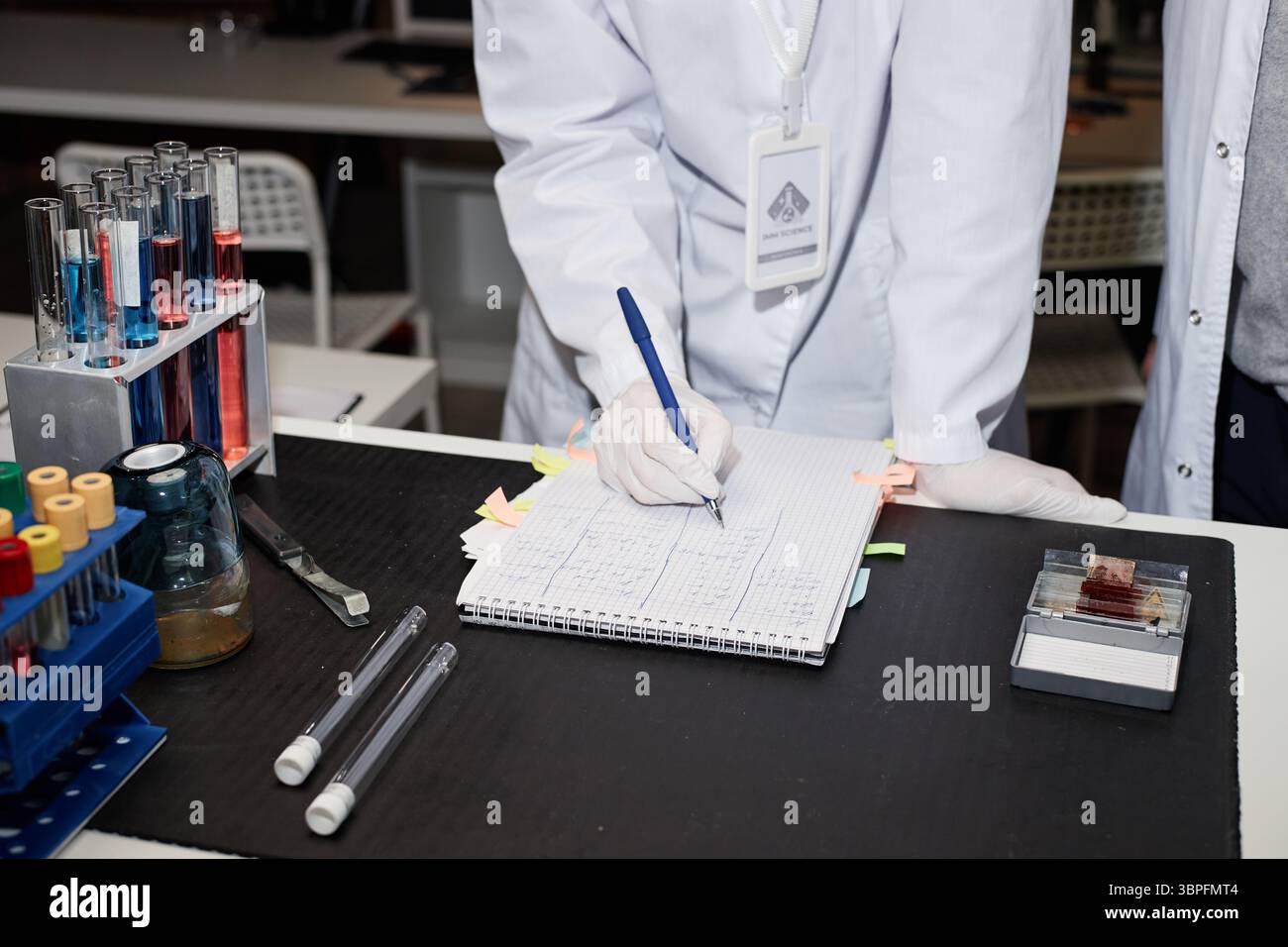 Unrecognizable Caucasian woman in lab coat writing scientific notes in ...