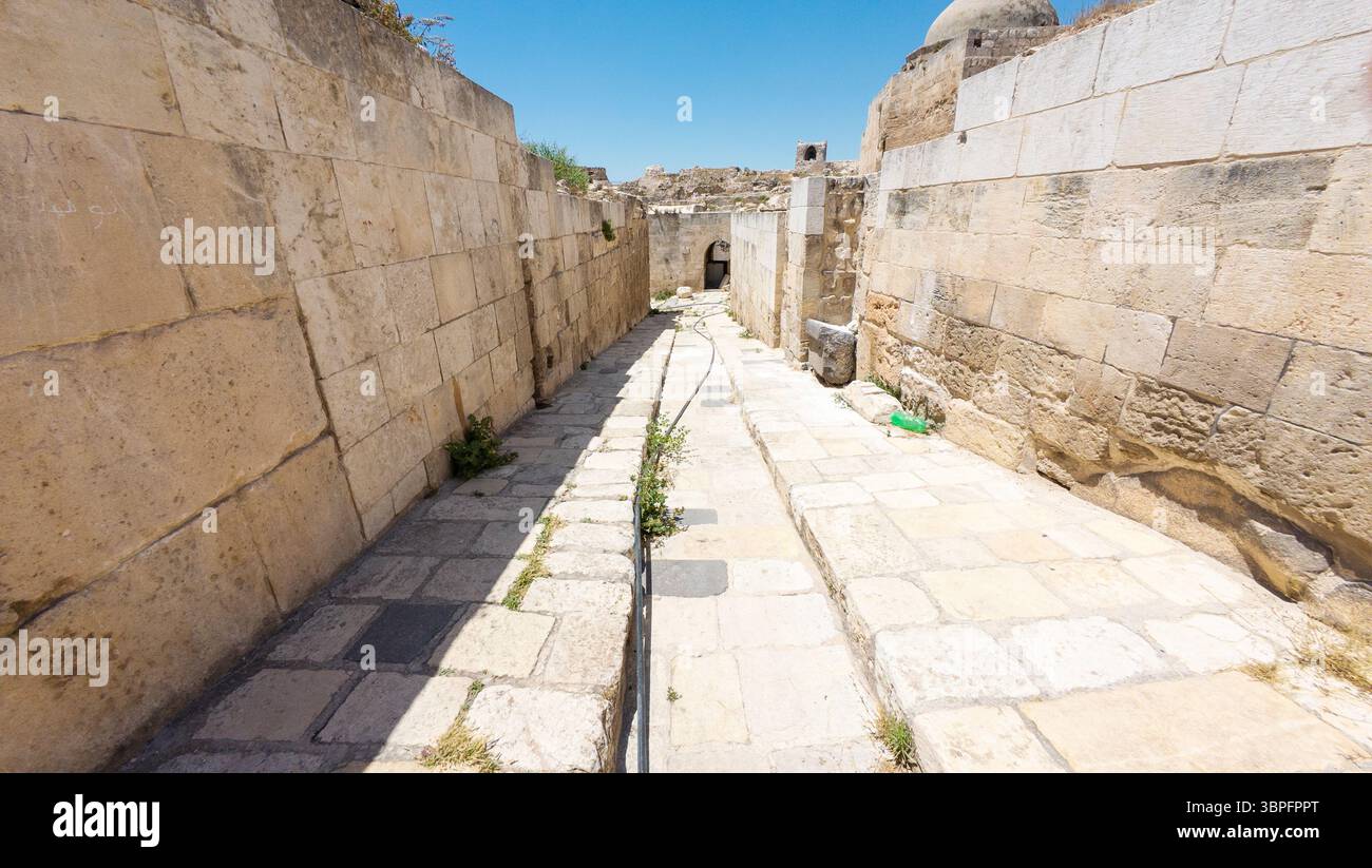 Ancient stone pathway with weathered walls under a clear blue sky ...