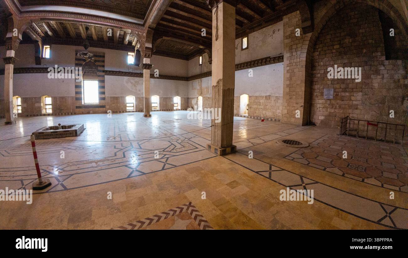 A spacious, empty historical hall with intricate floor patterns, stone ...