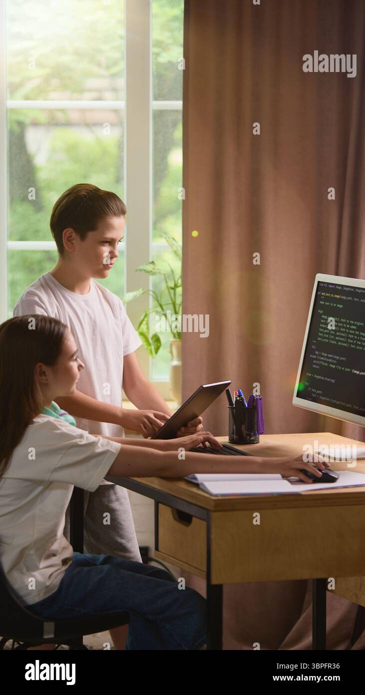 Kids learning to code on computer and tablet together at home. Fake ...