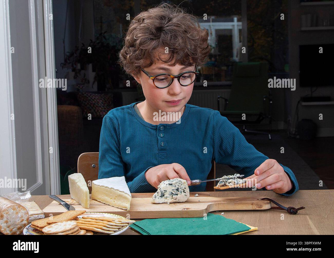 Netherlands, boy is spreading french cheeses on crackers. In front of ...