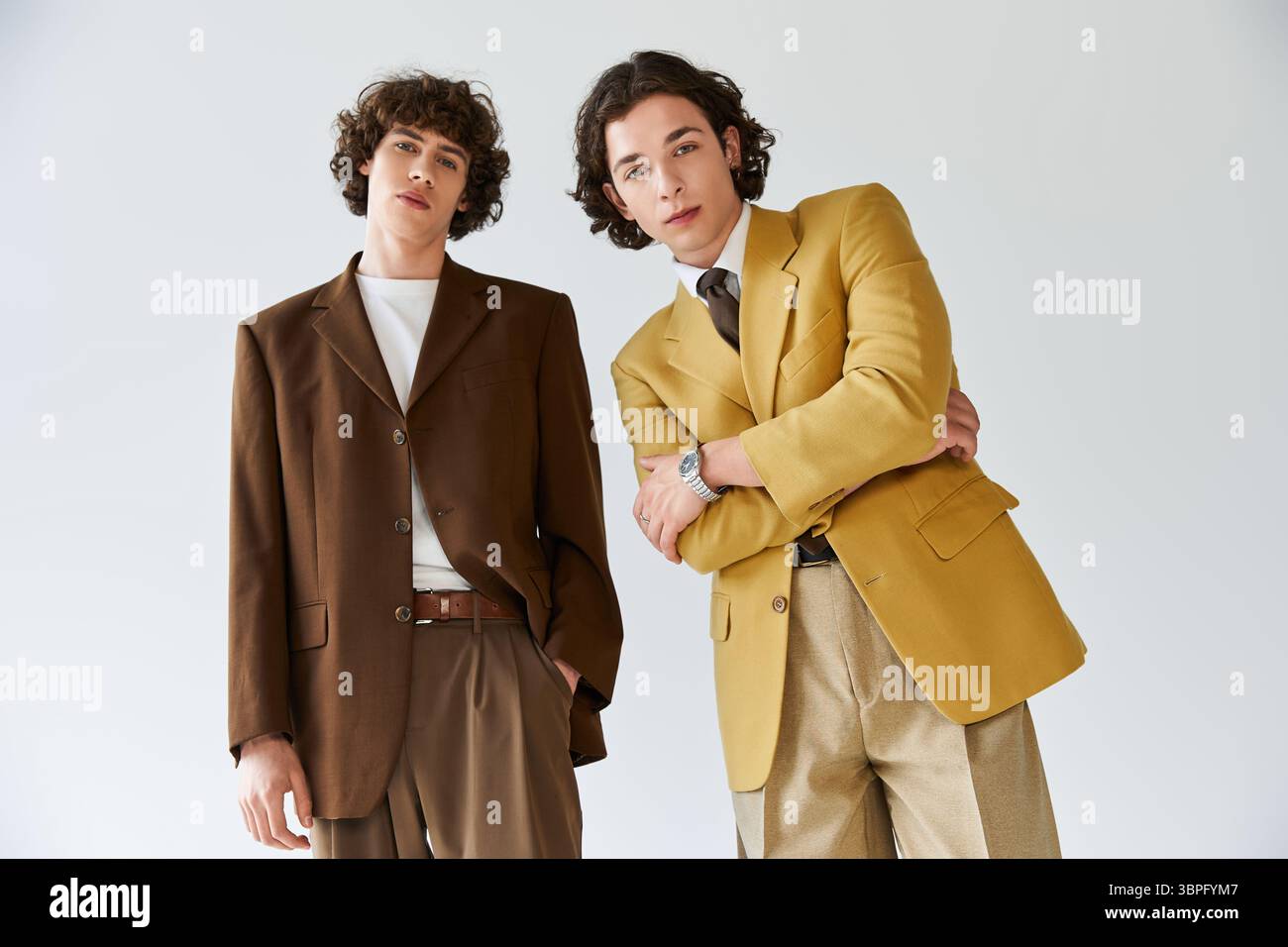 Two young men pose confidently in trendy outfits in a modern studio ...