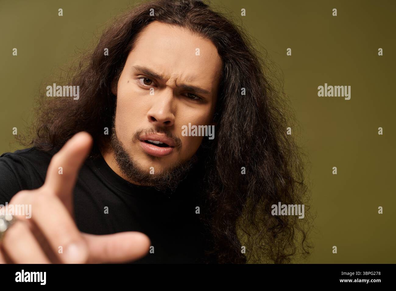 A bearded young man with long hair points forward, exuding boldness and ...