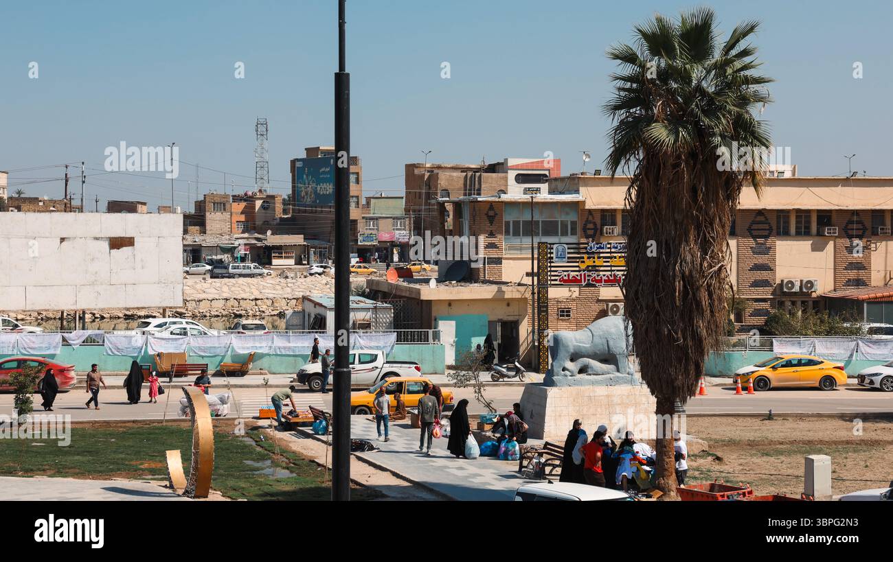 People engage in daily activities in Hilla Iraq, surrounded by palm ...