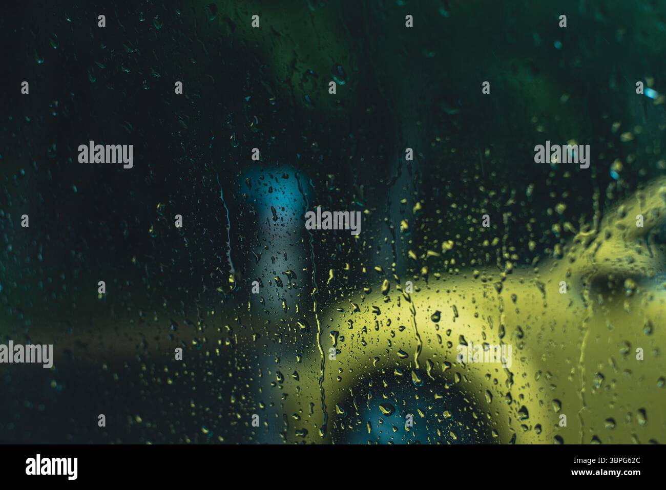 Raindrops stream down the car window, blurring the view outside. A ...