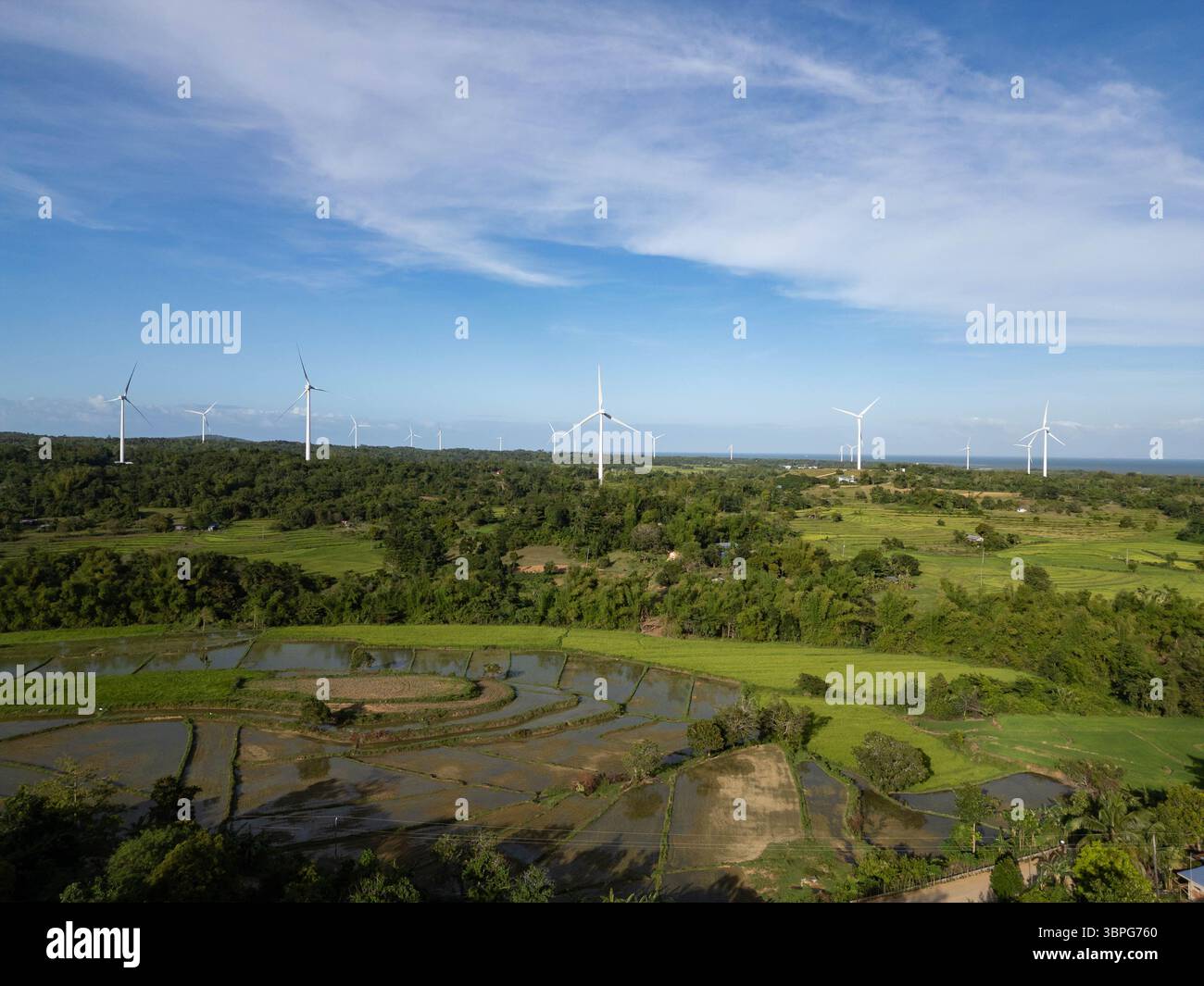 Aerial view of wind turbines standing tall amidst the lush green fields ...