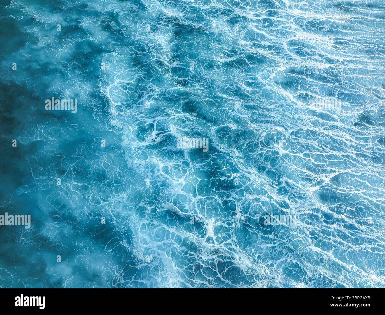 Aerial view of turquoise waters dance with frothy white crests, forming ...