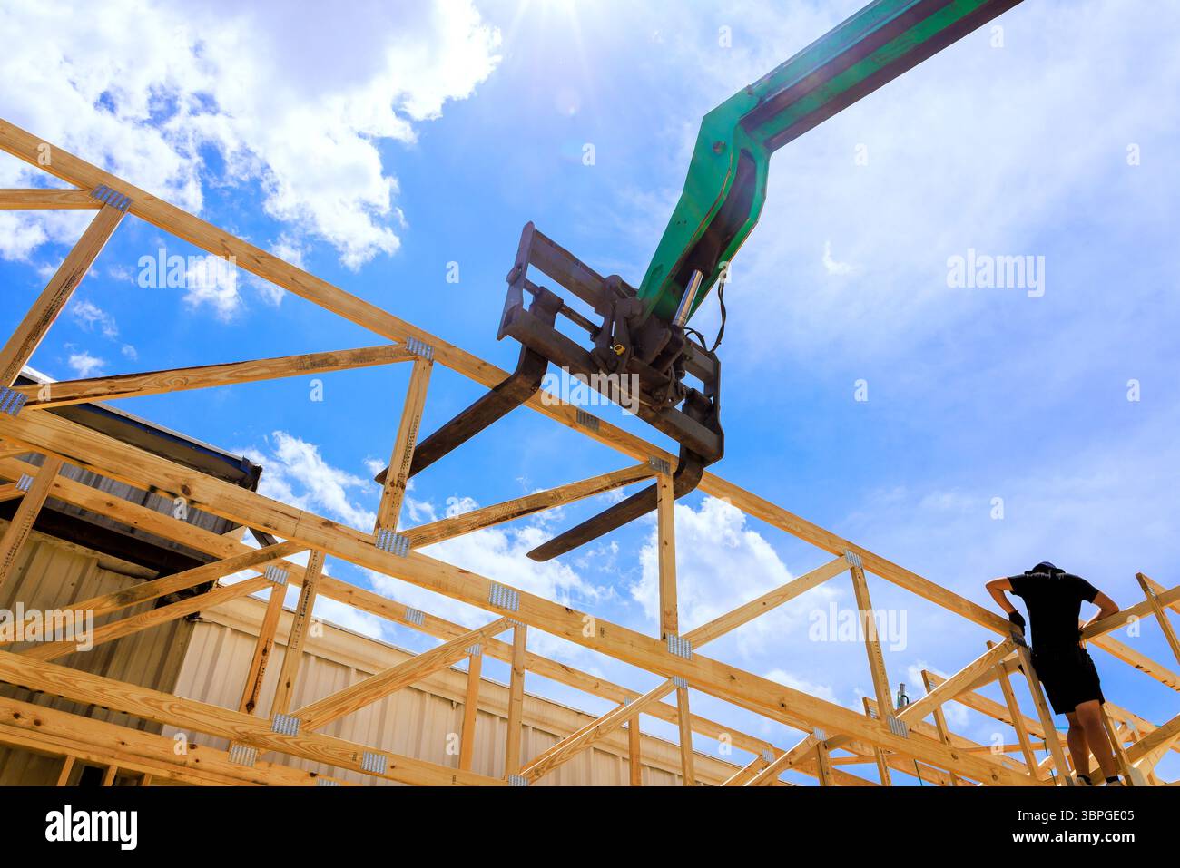 Worker positions wooden beams telehandler using machinery on ...