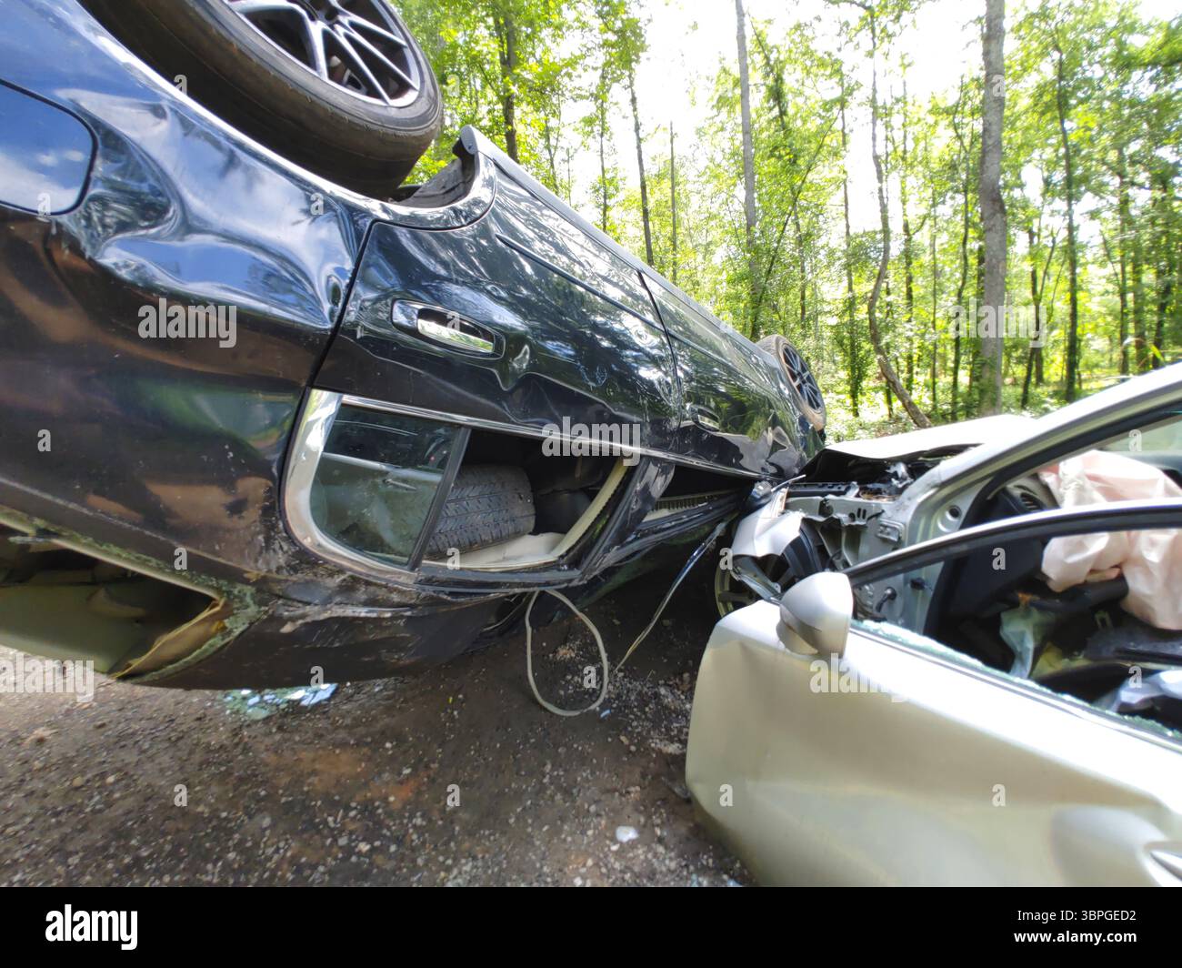 Two damaged cars involved in collision, with one vehicle flipped on its ...