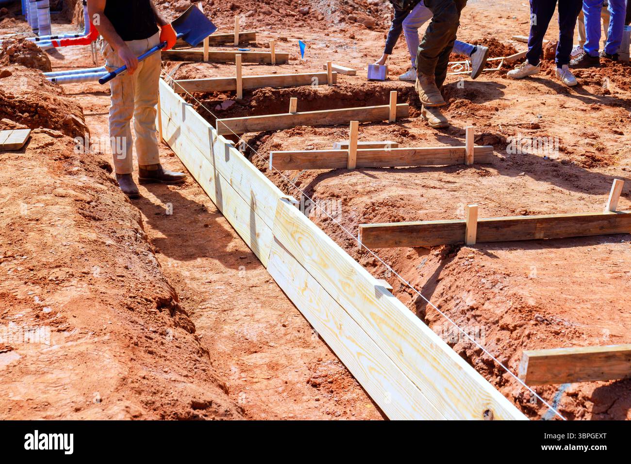 Workers are assembling wooden forms for foundation of new structure at construction site Stock ...