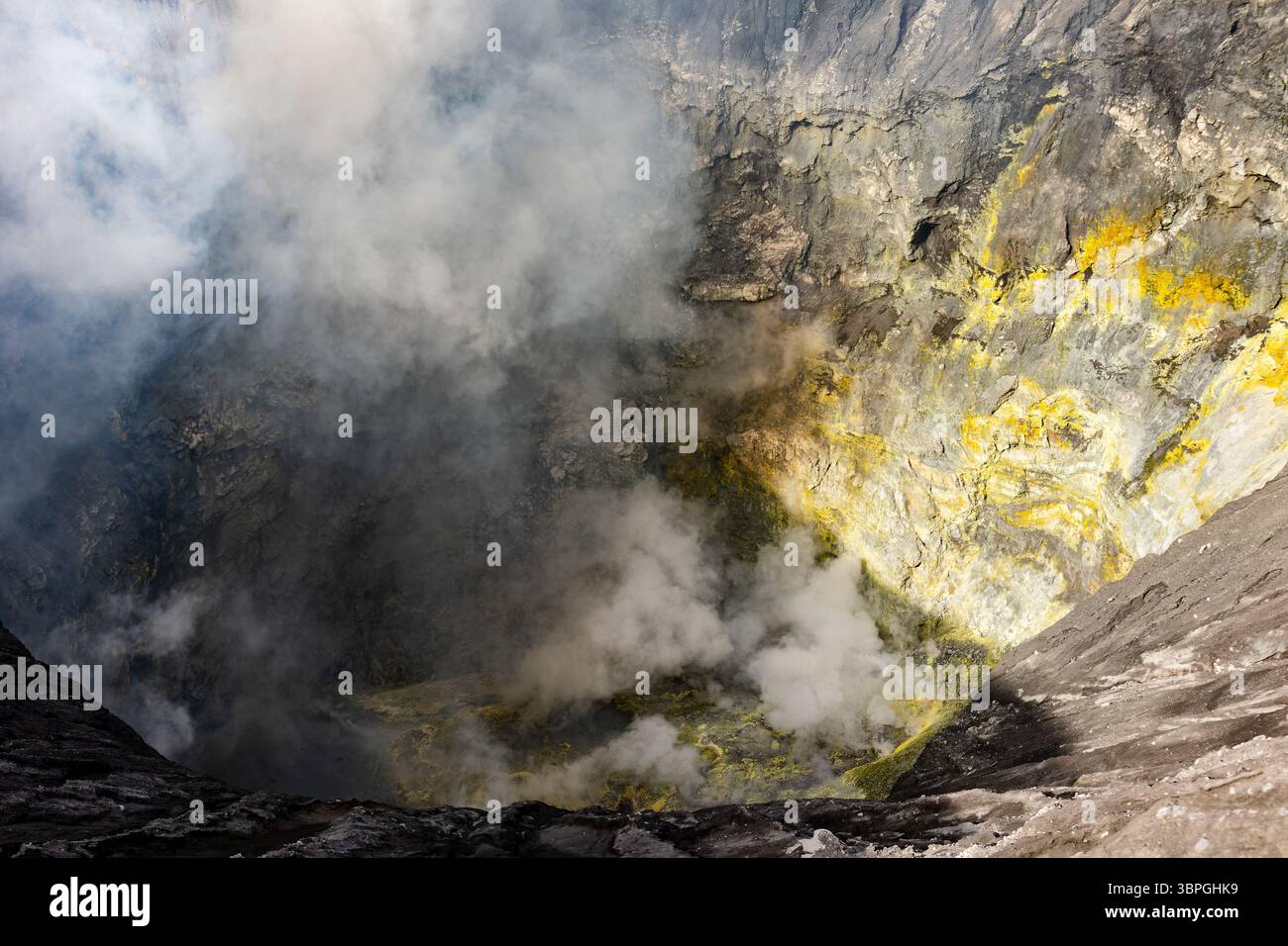 View of a smoking volcano crater with yellow sulfur deposits clinging ...