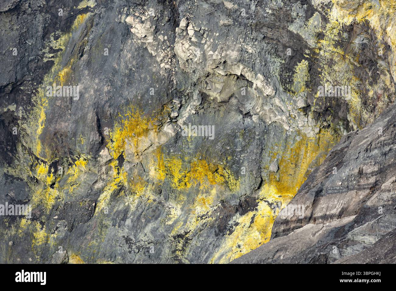 View of volcanic rock face streaked with vibrant yellow sulfur deposits ...