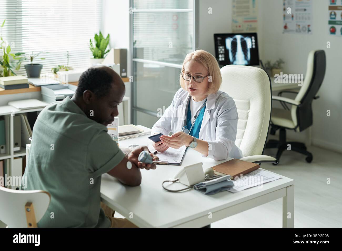 Middle aged Caucasian female doctor consulting middle aged Black man ...