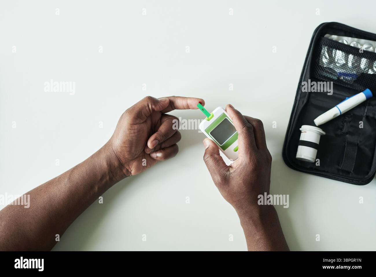 Black man using blood glucose meter checking blood sugar level with ...