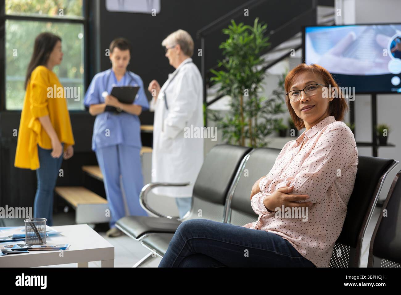 Portrait of smiling asian woman waiting in the medical facility lobby ...