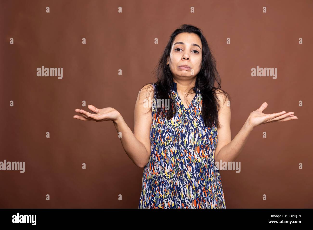 Confused indian lady with pursed lips and shrugged shoulders ...