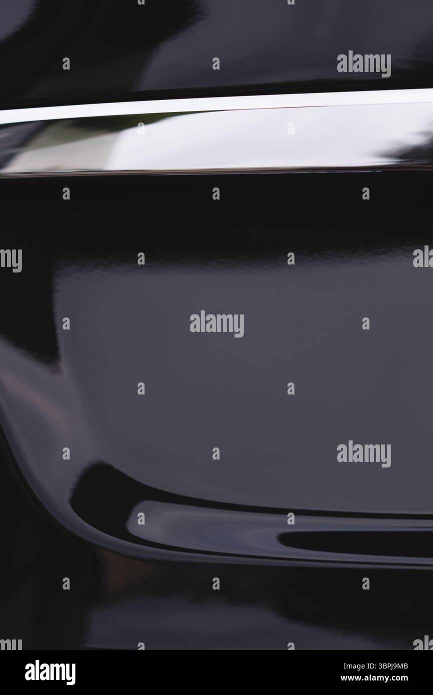 Glossy black vehicle panel is showing metallic silver trim running ...