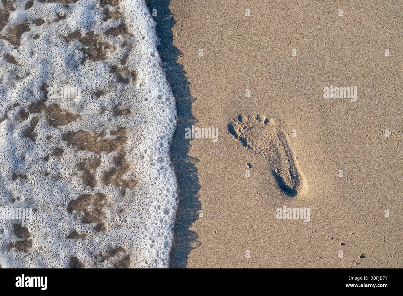 Single footprint on the beach being washed by the sea waves Stock Photo ...