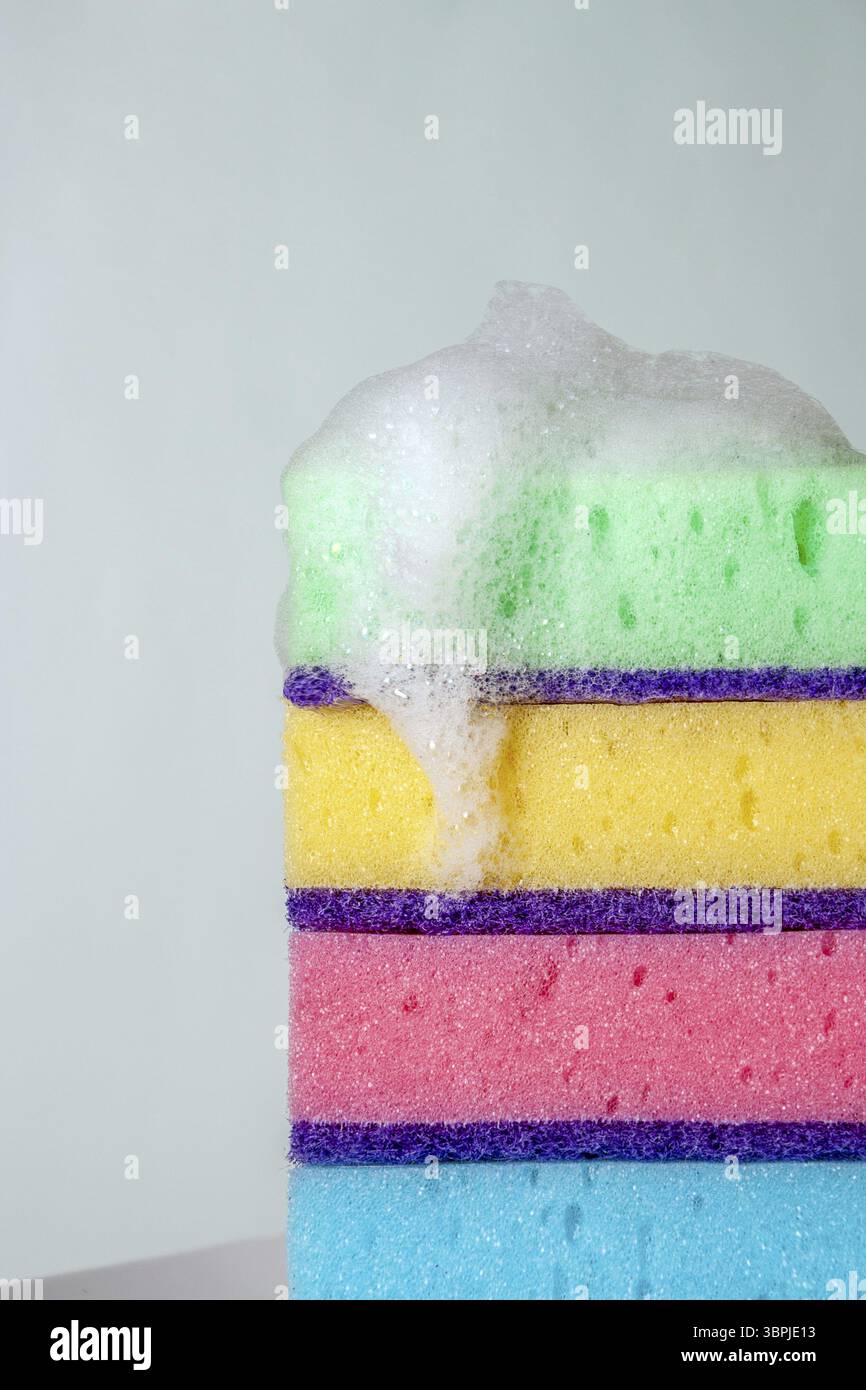 A stack of multi-colored sponges for washing dishes on a blue ...