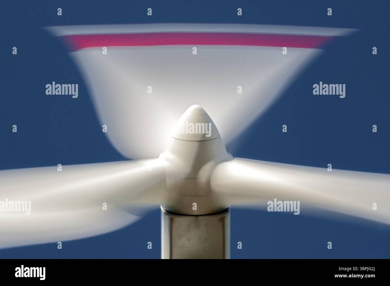 White rotor blades of a wind turbine blurred by motion blur against a ...