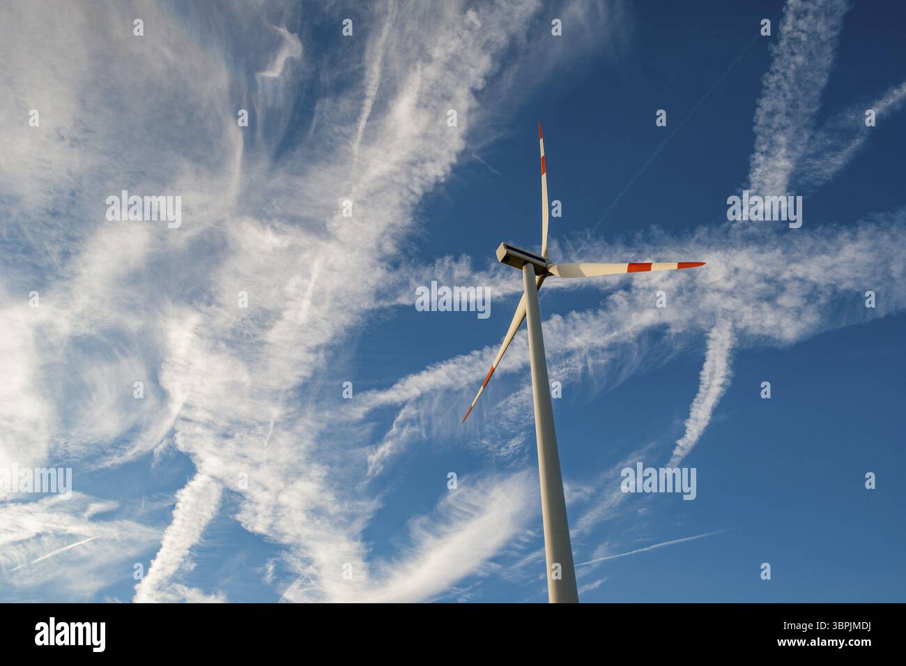 Rotor blades of a wind turbine in front of a blue sky with contrails ...