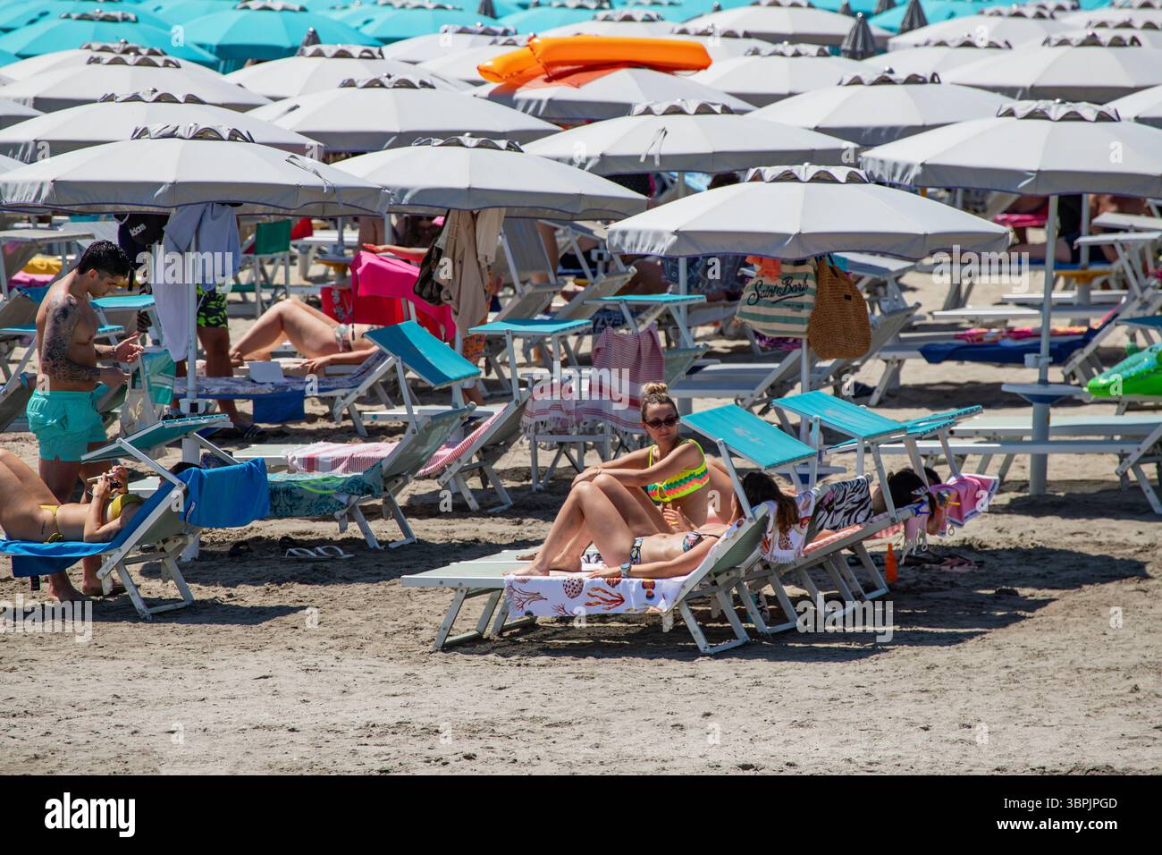 Summer beach day with many colorful umbrellas sun loungers people ...