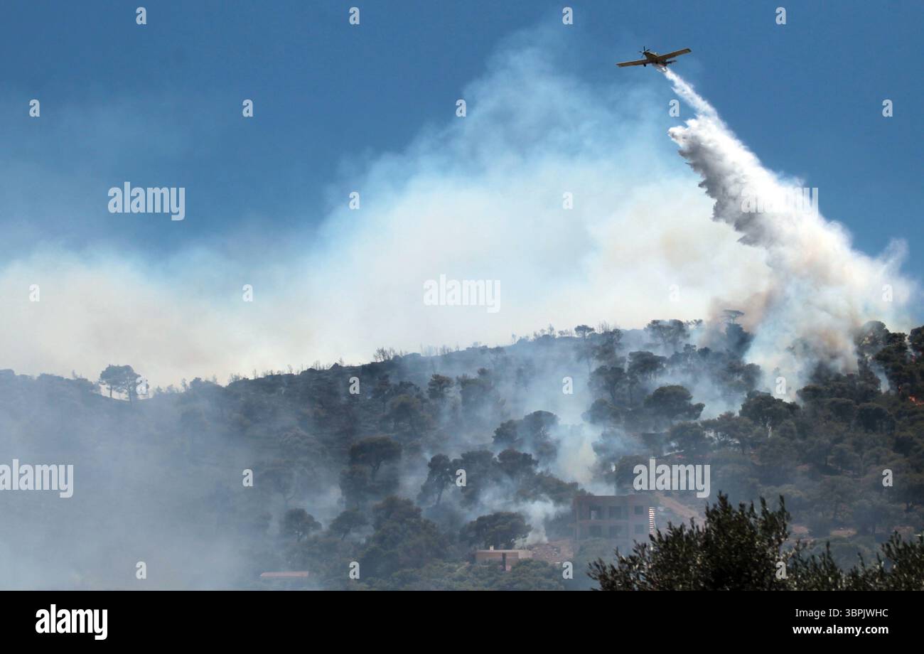 A firefighting airplane drops water as a wildfire burns at Aghios ...