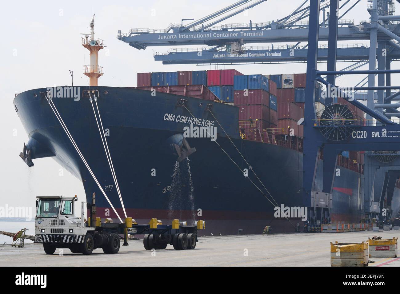 A truck drives past a ship loaded with containers at Jakarta ...