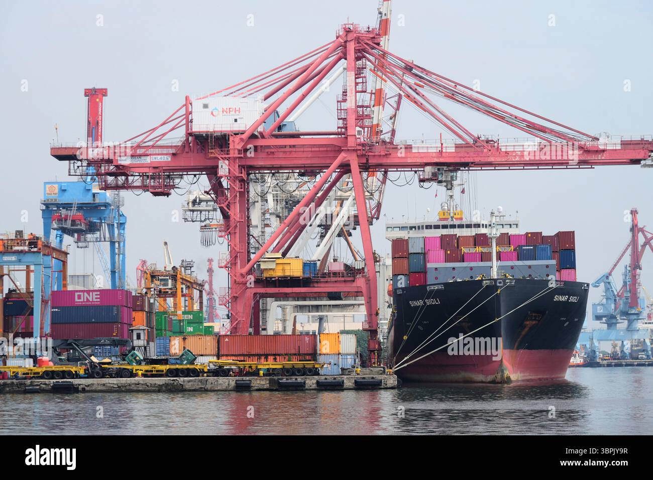Cranes load shipping containers onto a cargo ship at Jakarta ...