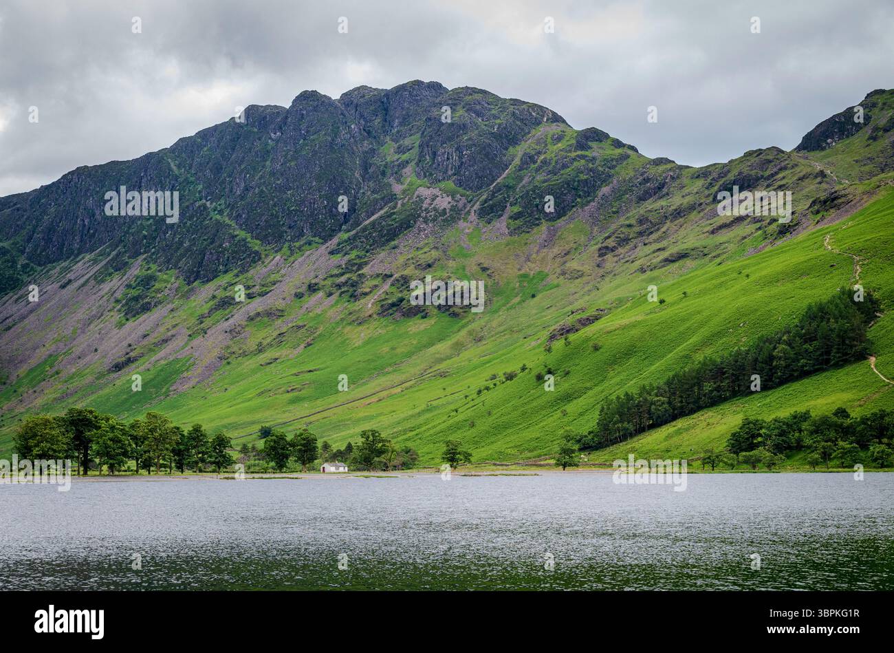 A cropped view of a majestic rocky fell rising above Buttermere Lake ...