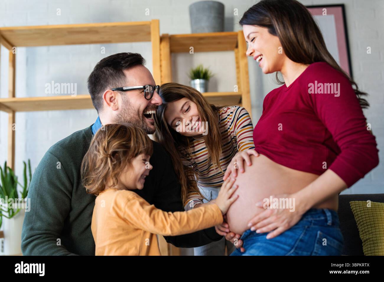 Happy excited pregnant mother, father and siblings spending free time ...